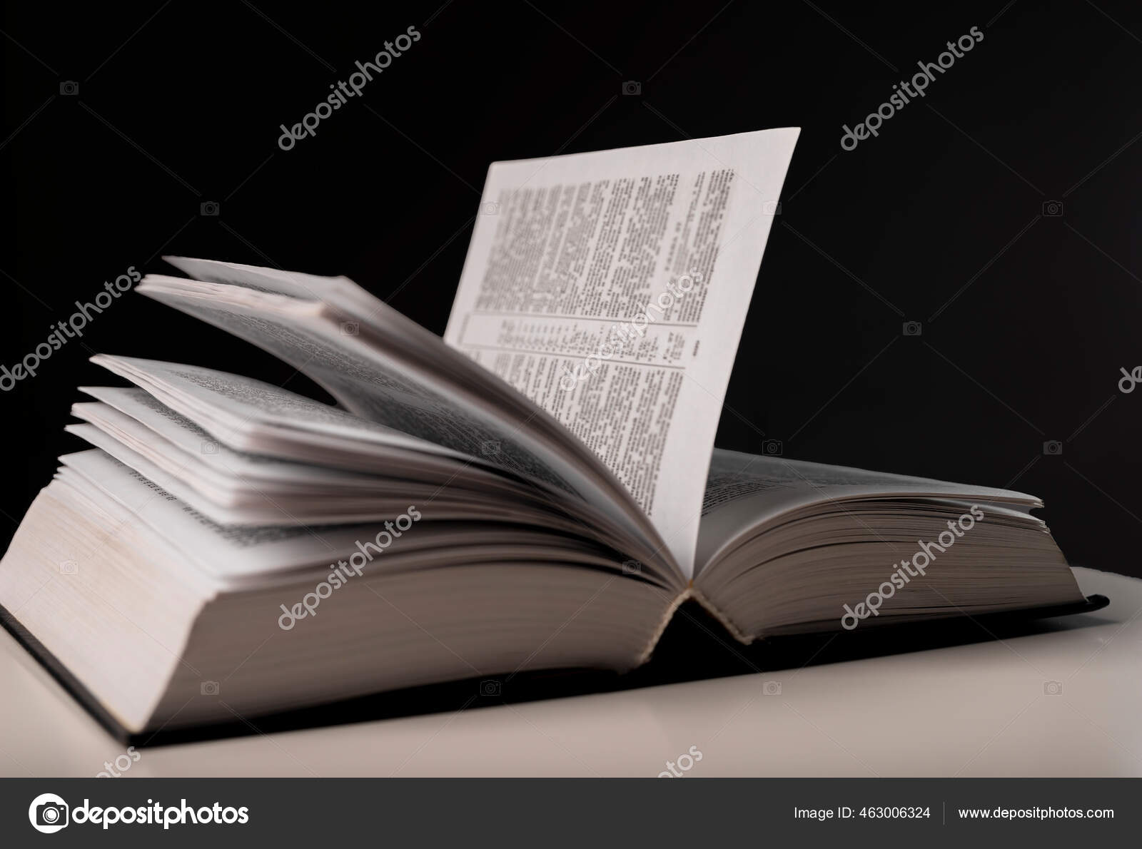 Open book with turning pages. Textbook in hard cover on table ...