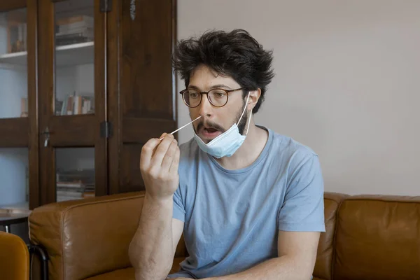 Portrait of concentrated young man taking a Self-swabbing home tests ...