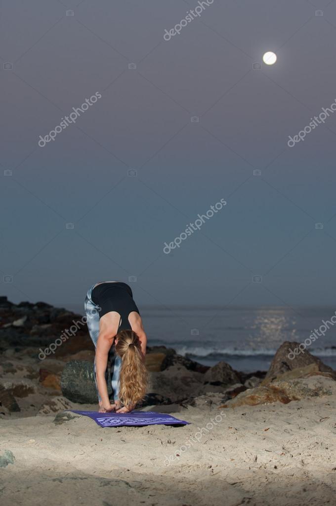 Blond woman in pattern tights performing standing hamstring stretch at ...