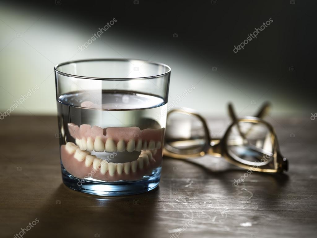 Dentures in a glass of water — Stock Photo © Arrfoto #74356991