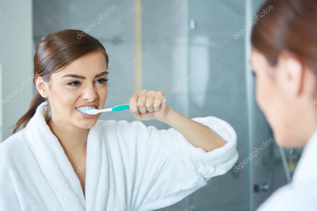 Young pretty woman brushing teeth — Stock Photo © 2mmedia #65298913