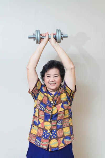 Strong Asian senior woman lifting weights, in studio shot, speci ...