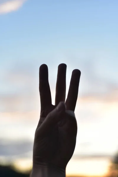 La mano está contra el cielo azul, el dedo meñique y el pulgar están en ...