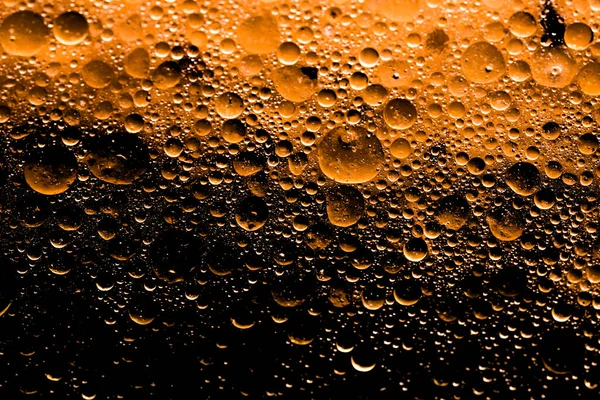 Close-up of an orange substance with bubbles and water droplets ...