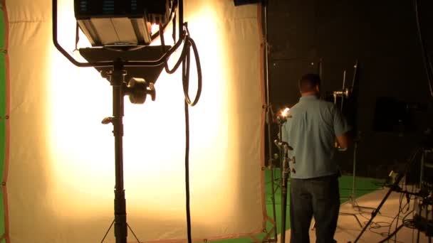 Professional grip on a film set sets up a stand and walks off frame ...