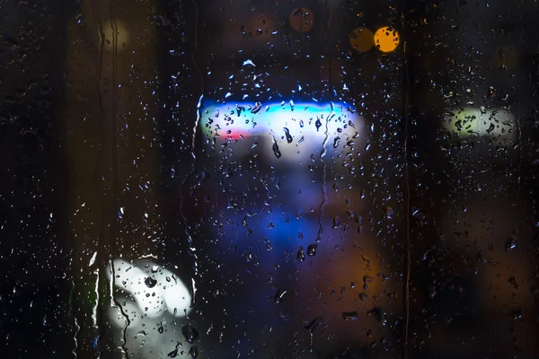 Raindrops on the window with urban night lights — Stock Photo ...
