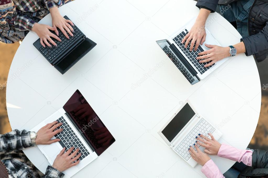 Top View of Rounded Desk with Four Laptops and People Hands Typing on ...