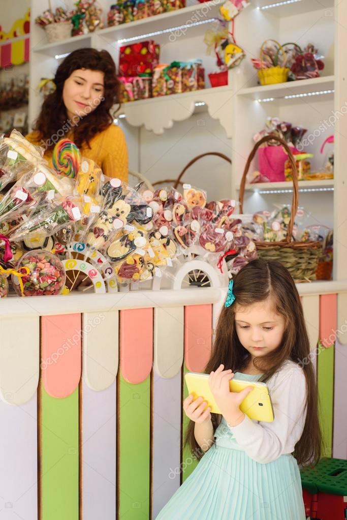 Little girl using tablet computer in candy store — Stock Photo ...