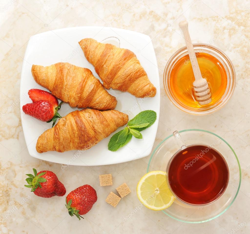 Morning Breakfast - croissants with tea and honey. Spoon for hon ...