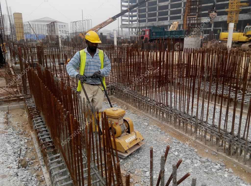 Builder worker at sand ground compaction with vibration plate compactor ...