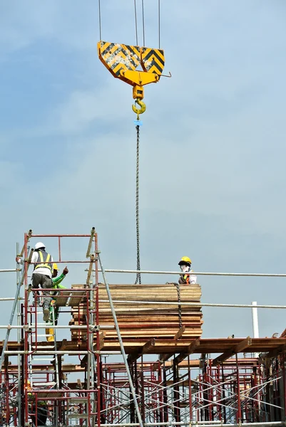 Group of construction workers lifting bundle of timber using mobile ...
