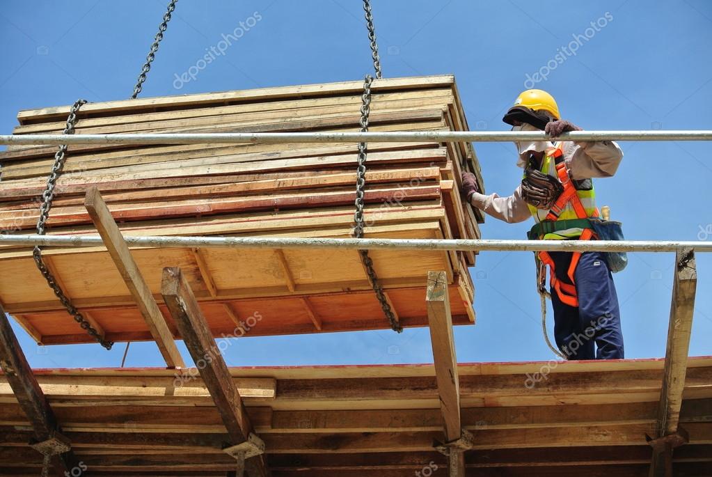 Group of construction workers lifting bundle of timber using mobile ...