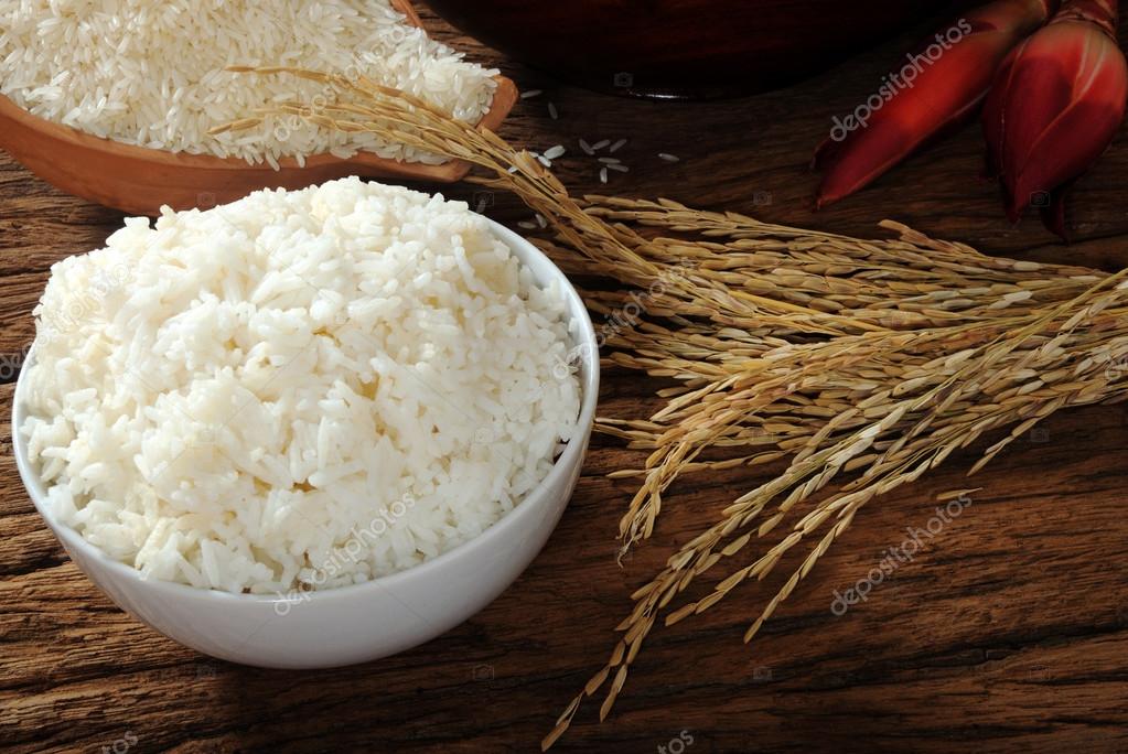 Cooked rice, uncooked rice and paddy rice on wooden table Stock Photo ...