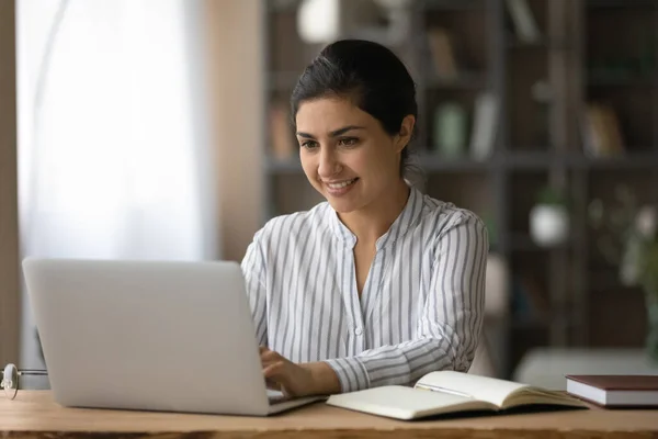 Smiling Indian woman using laptop, studying online at home - Stock ...