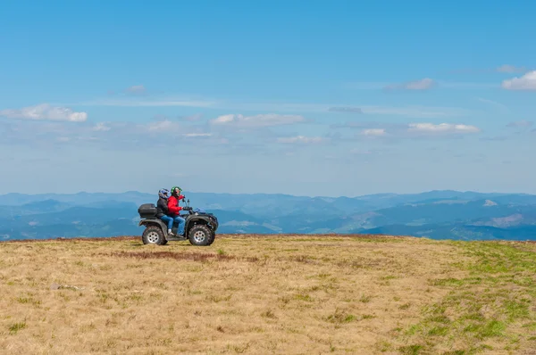 Quad biking in the mountains. Equipped ATV driver and passenger ...