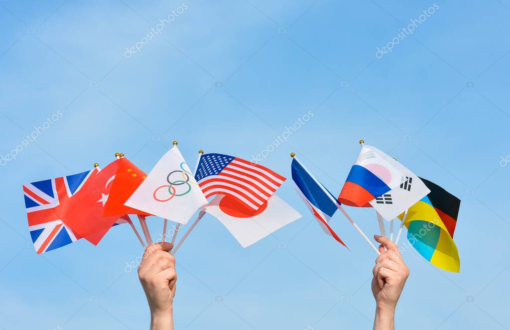 J rkov, Ucrania, 23 de mayo de 2021. Banderas ol mpicas en las manos sobre el fondo del cielo ...