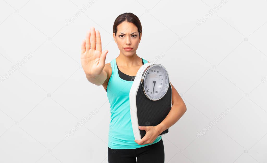 joven mujer hispana mirando serio mostrando la palma abierta haciendo ...