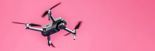 Flying drone with camera on pink background with copy space. Airborne ...