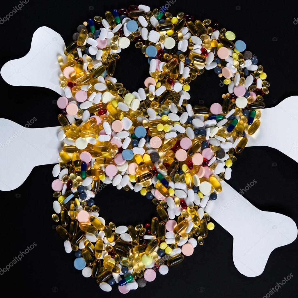 Tablets, pills and capsules, that shape a creepy skull, on black ...