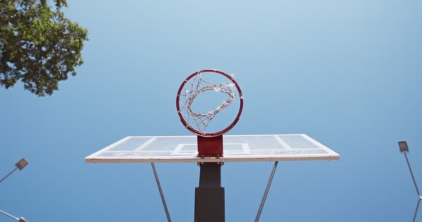 Below view of black basketball ball falling into loop at outdoor ...