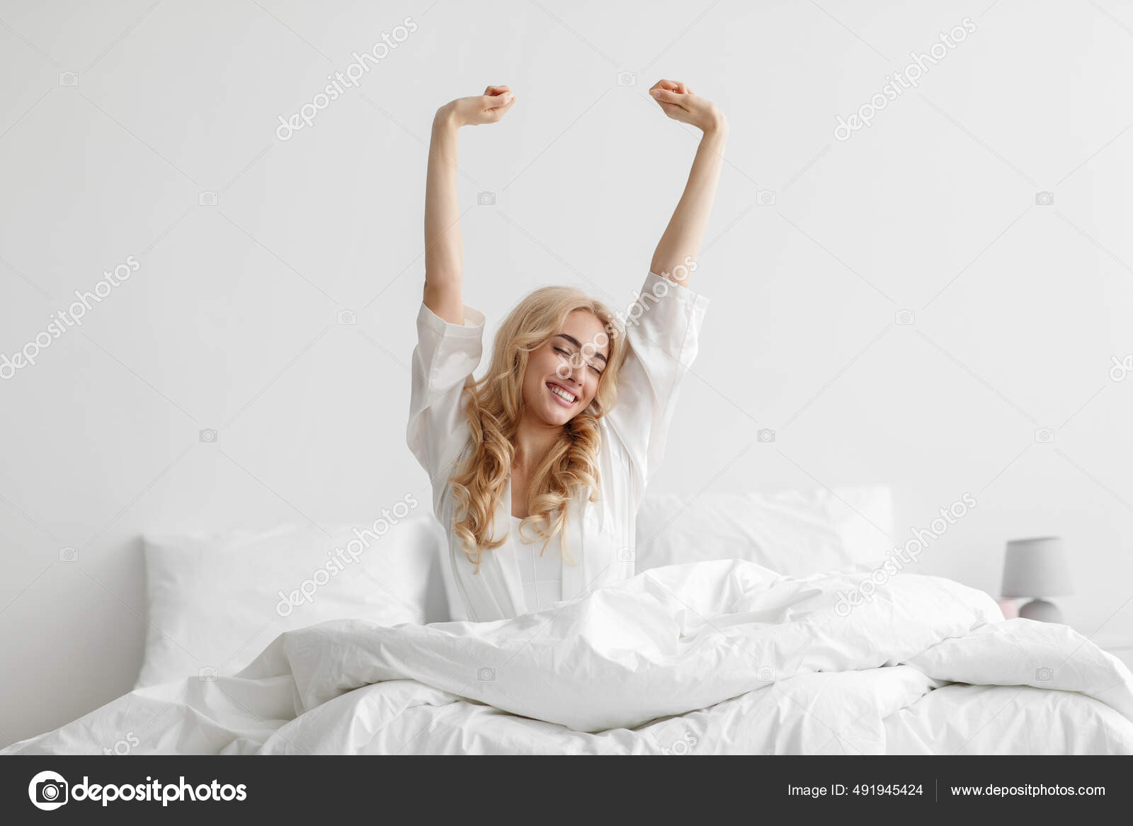 Good morning, smiling young lady waking up fully rested on white ...