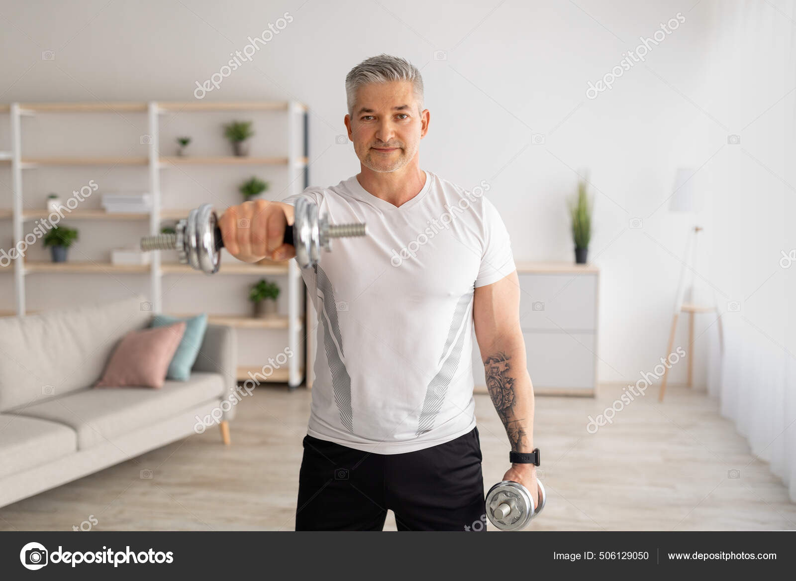 Domestic training with weights. Positive mature man doing exercises ...