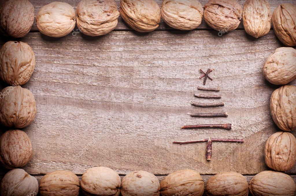 Simple frame arranged from walnuts on wooden background with Christmas ...