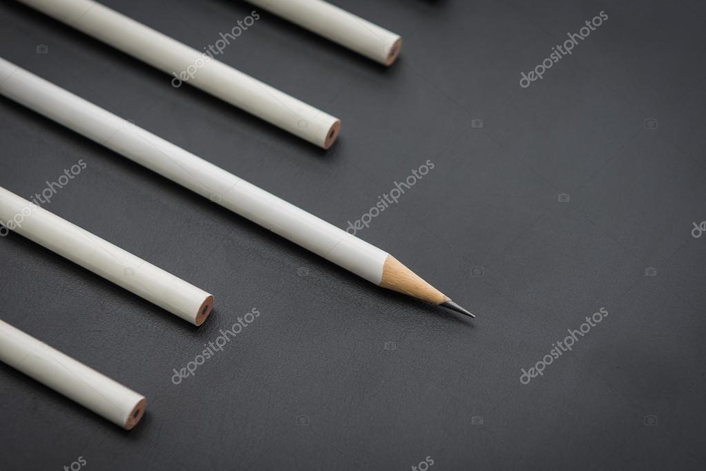 One white pencil among many pencils on black Stock Photo by ...