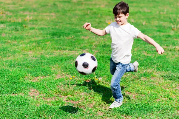 Pretty male child playing football on grass Stock Photo by ...