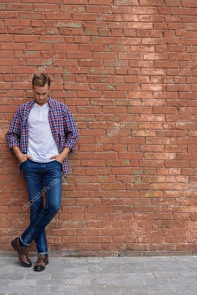 Handsome guy standing near brick wall Stock Photo by ©iakovenko123 ...