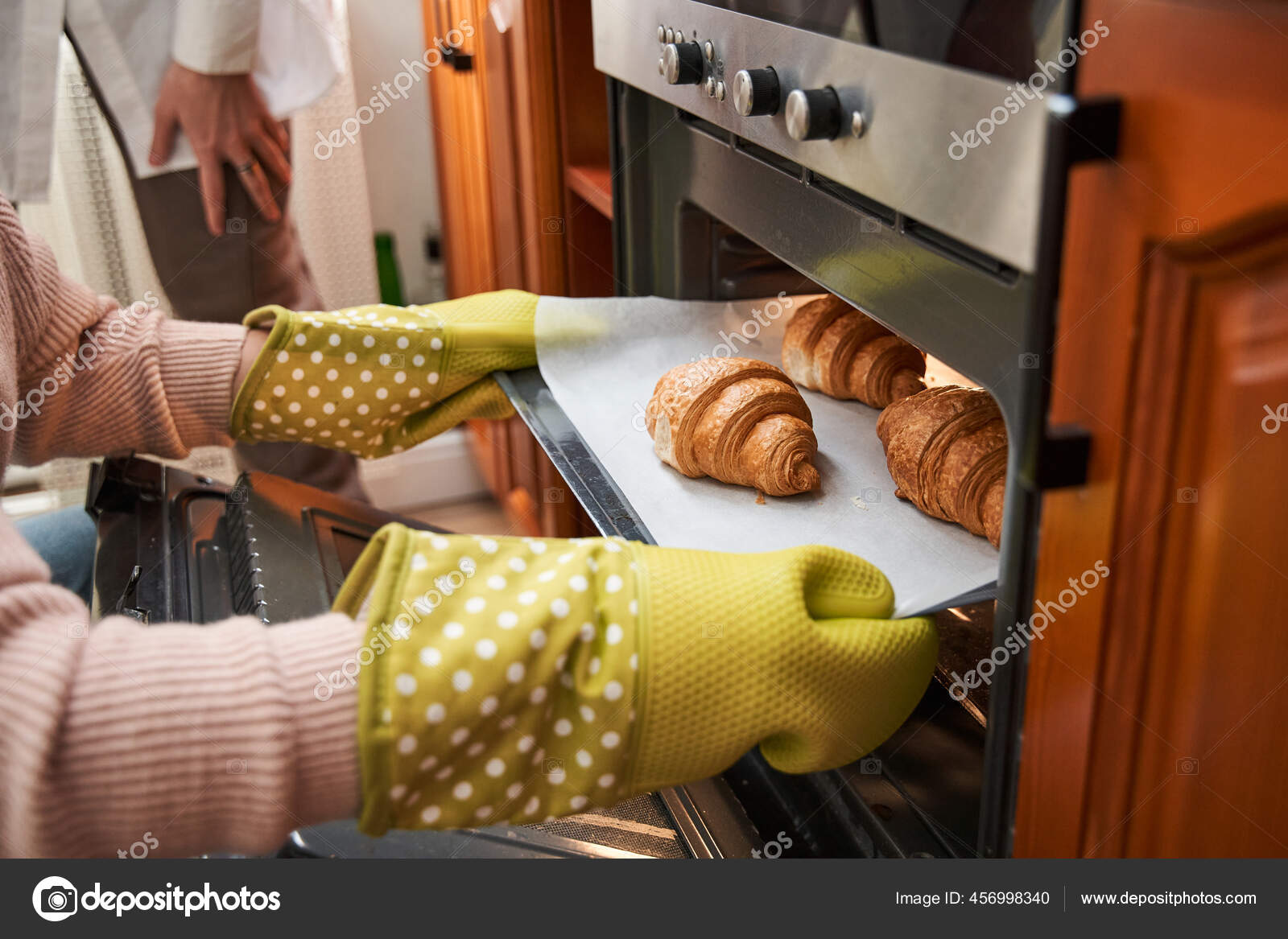 Women using glove for get out pan of own while preparing croissants ...