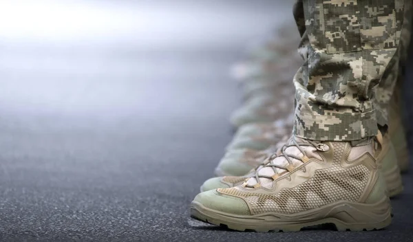 The soldiers' legs are dressed in ankle boots and camouflage pants. Close-up, selective focus ...