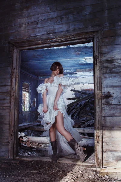A beautiful bride in a ragged wedding dress is standing at ruine ...