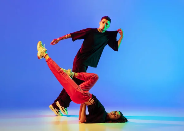 Two young people, man and woman dancing brakedance, hip-hop over blue ...