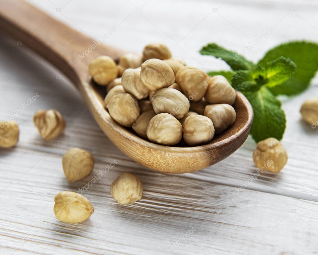 Avellanas peladas en una cuchara sobre fondo de madera blanca 2024