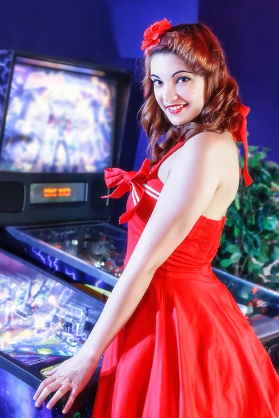 Style pinup girl in red dress, play pinball. — Stock Photo © Polifoto ...