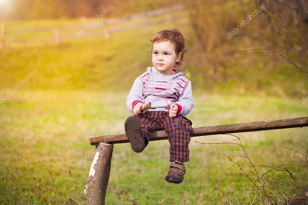 A little boy is sitting under a tree. Stock Photo by ©zhukovvvlad 107708376