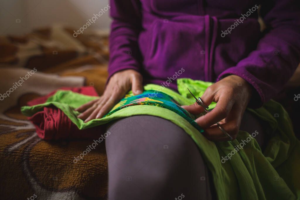 Una mujer cose un parche en la ropa rasgada de un calcetín viejo ...