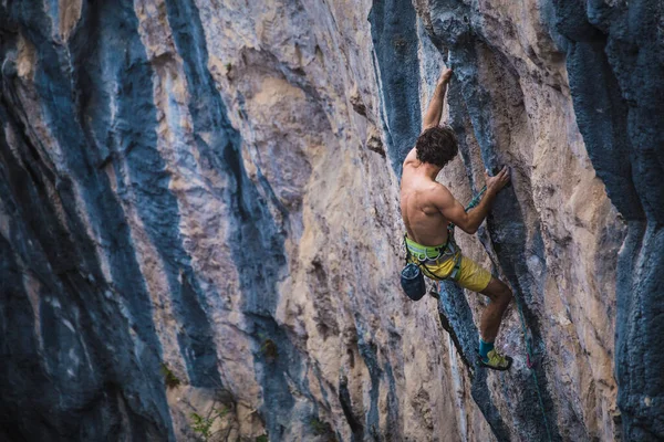 A strong man climbs a rock, Strong back muscles, Rock climbing in ...