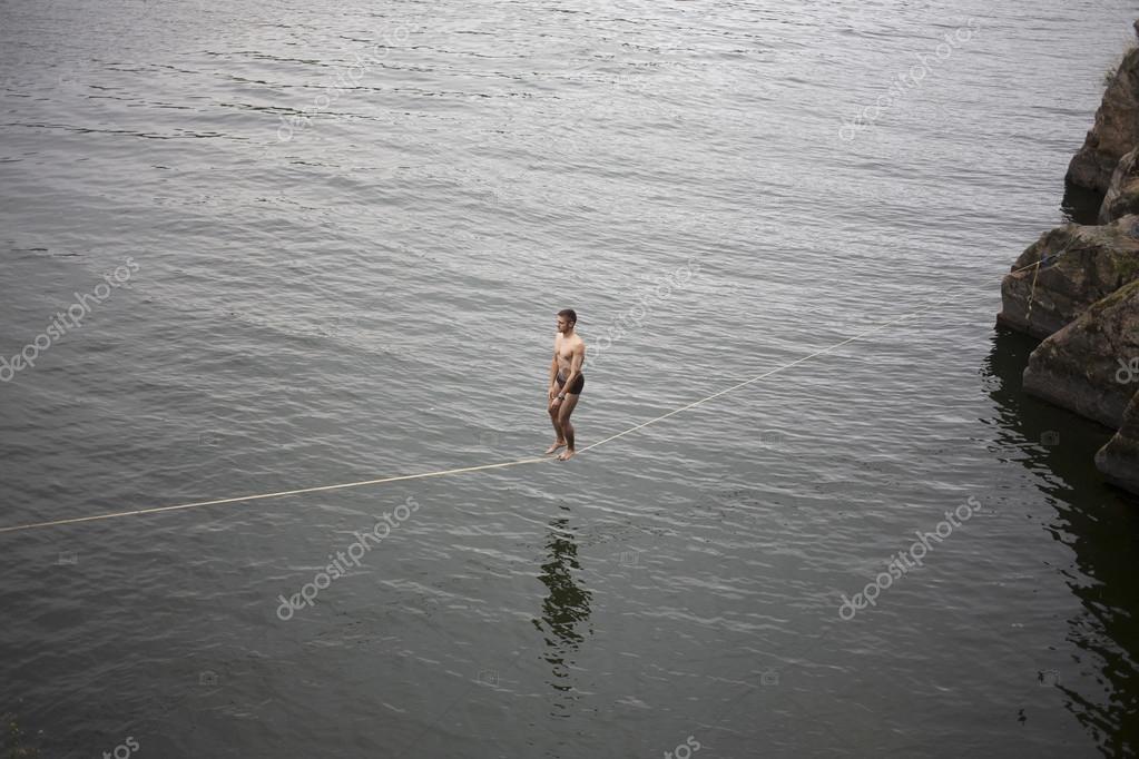 Young man walking on a rope over water. Stock Photo by ©zhukovvvlad ...