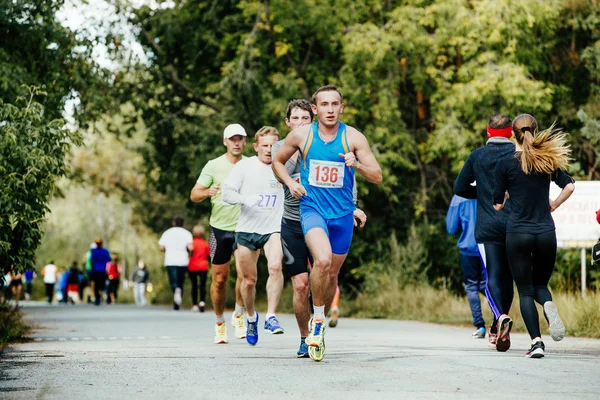 Large group of runners men middle-aged and young run through Park ...