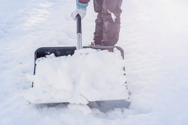 Close up of a person clearing snow from the sidewalk with a snow shovel ...