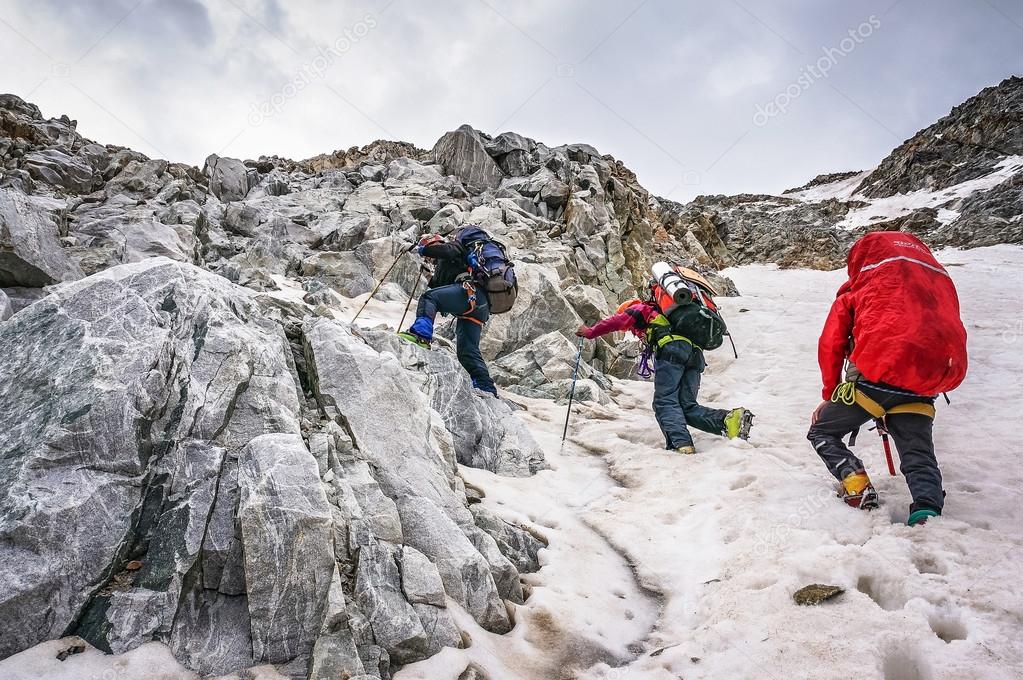 Group of climbers ascent to the mountain on a complex slope is composed ...