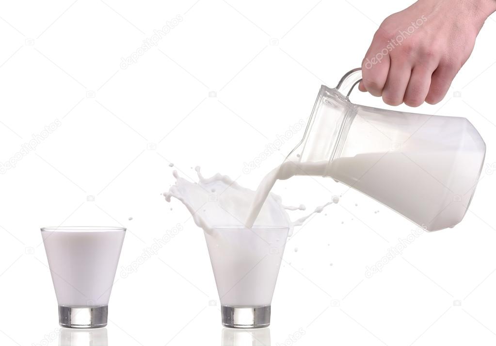 Pouring milk from jug bottle in a glass with splash on white background ...