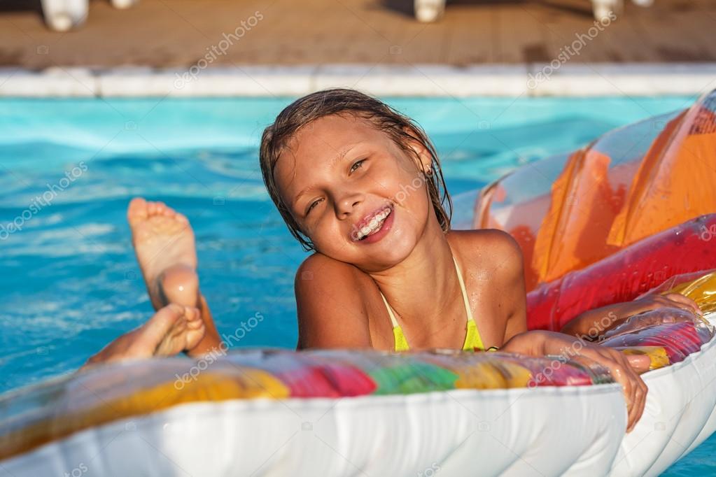 Chica feliz jugando en agua azul de la piscina. 2023