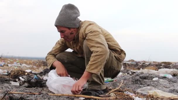 Dirty homeless man sits on a close-up of the trash and eat the bread of ...