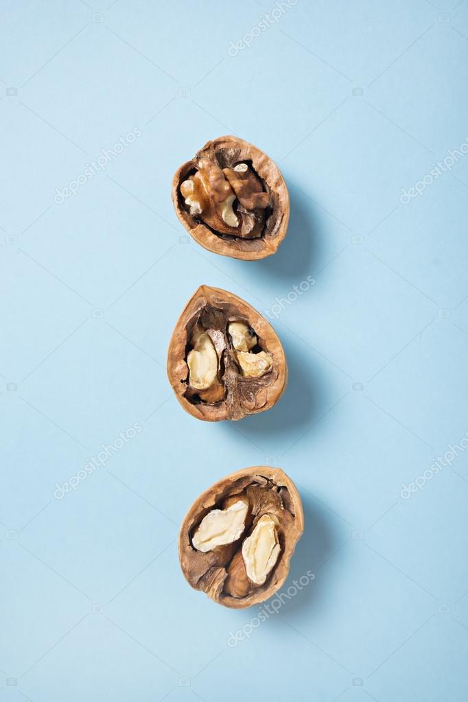 Walnuts whole in their skins, chopped on blue background Stock Photo by ...