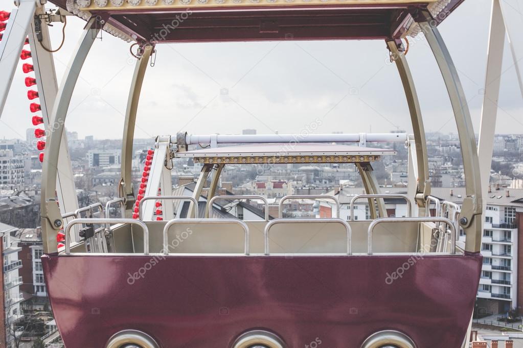 Empty retro ferris wheel cabin over blue skies and city view from high ...
