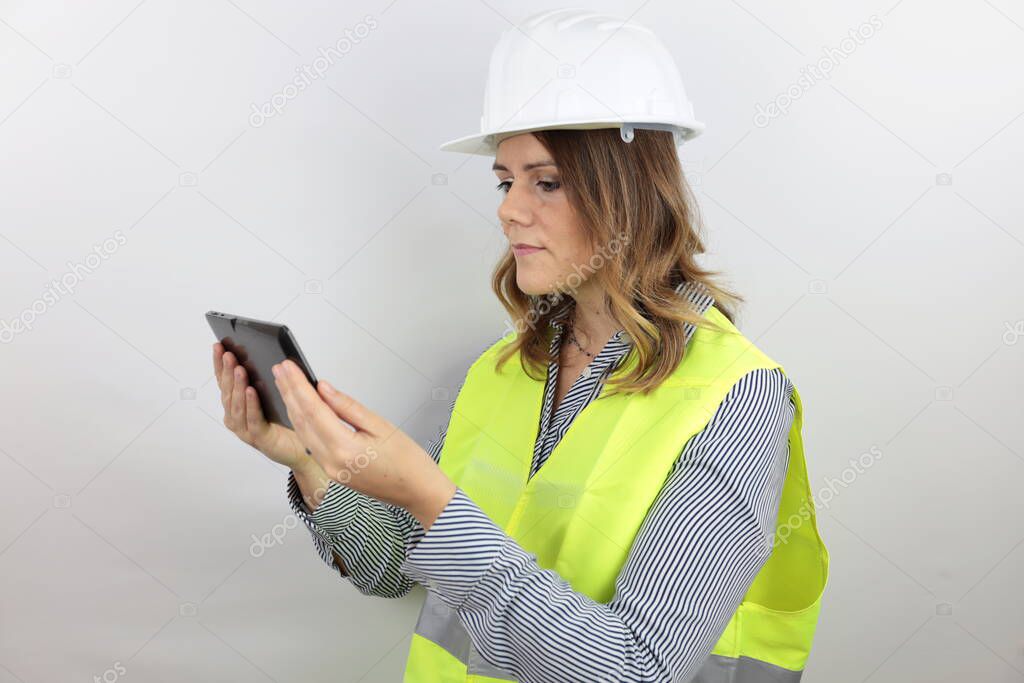 Arquitectora o ingeniera vestida con casco, aislada sobre fondo blanco de pie sosteniendo la ...