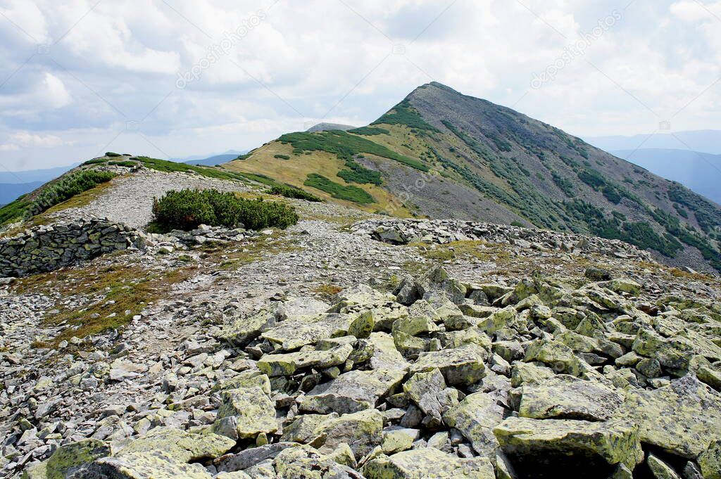 una cresta de piedra de montaña con piedras en primer plano y una punta ...